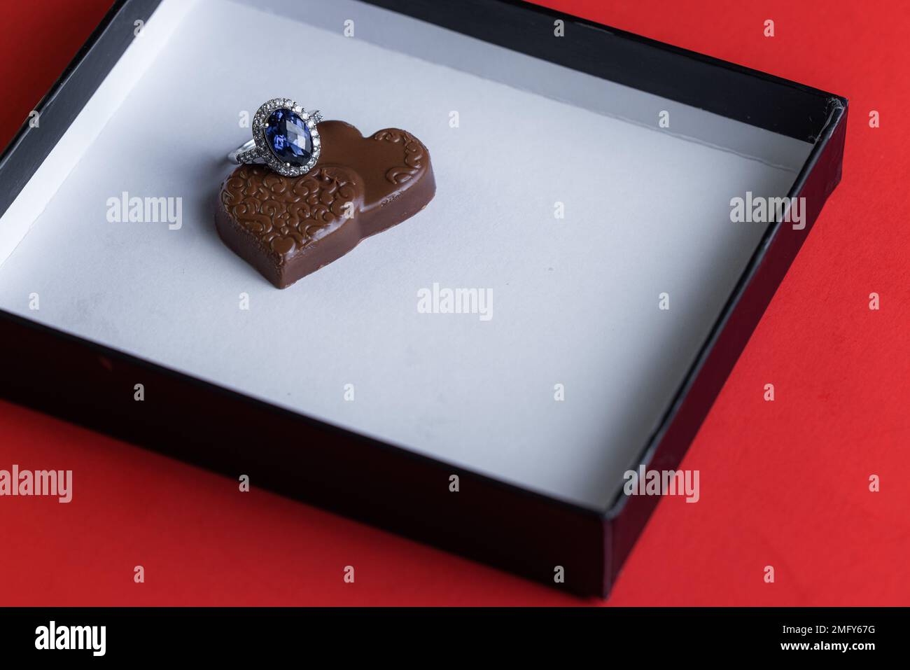 Blue sapphire ring with chocolates inside a white box on a red ...