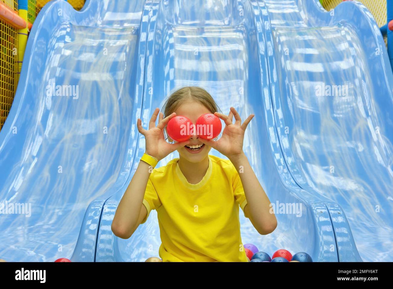 A funny girl is having fun playing with colorful balls in the game ...