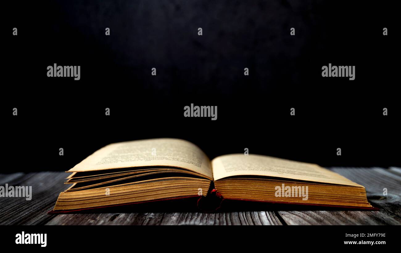 Image of an open antique book on a wooden table with old yellow sheets ...