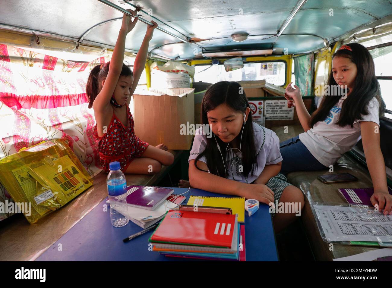 Grade school student Bhea Joy Roxas, center, uses a smart phone as she joins online classes ...