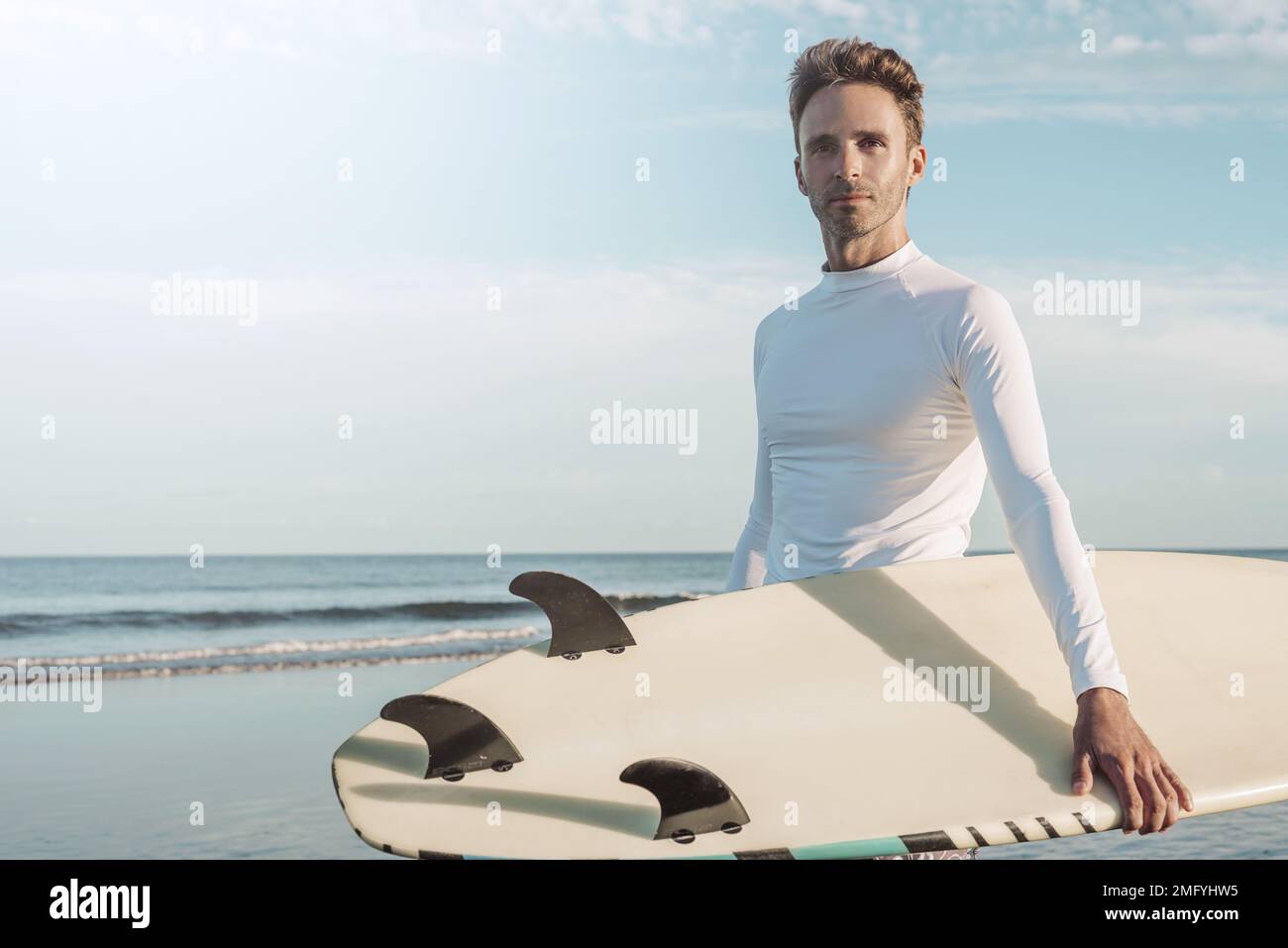 Young handsome surfer guy wearing an empty blank lycra t-shirt and ...
