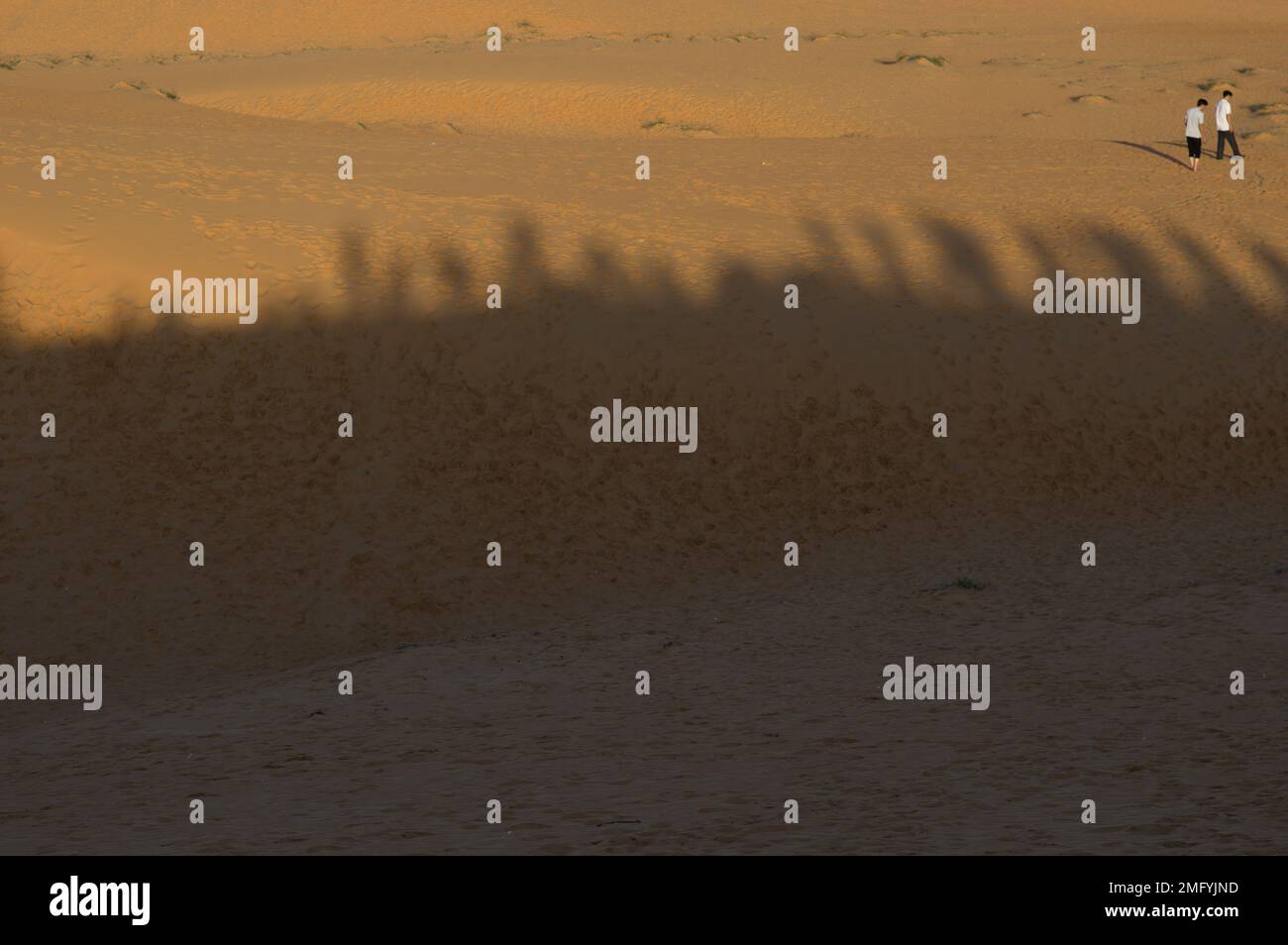 Two people walk in the disance on the red sand dunes in Mui Ne, Phan ...