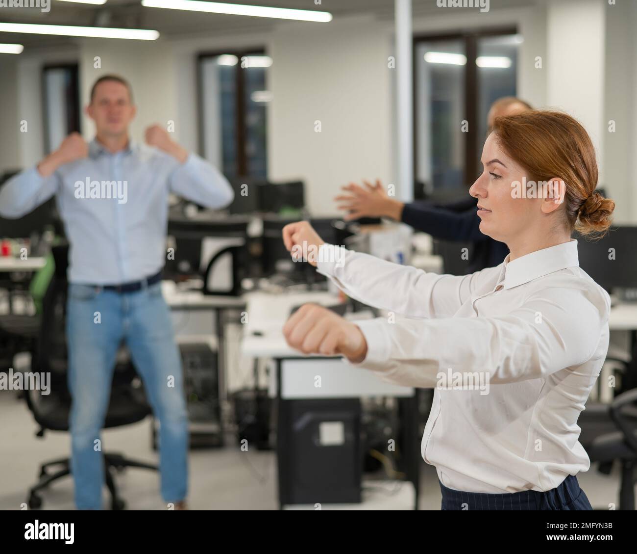 Three office workers warm up during a break. Employees do fitness ...