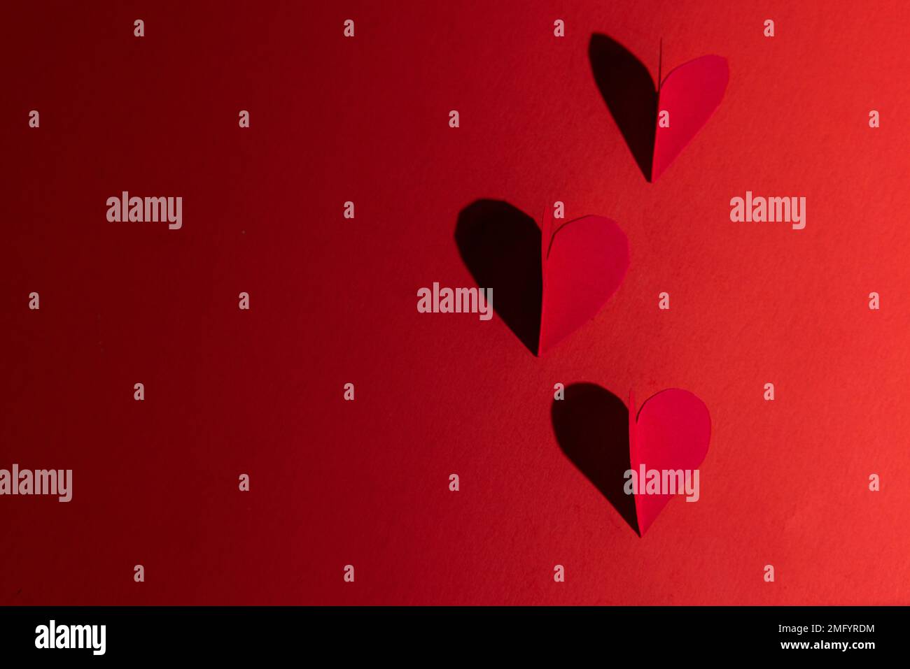 Heart cut out casting a shadow on a red background using direct light ...