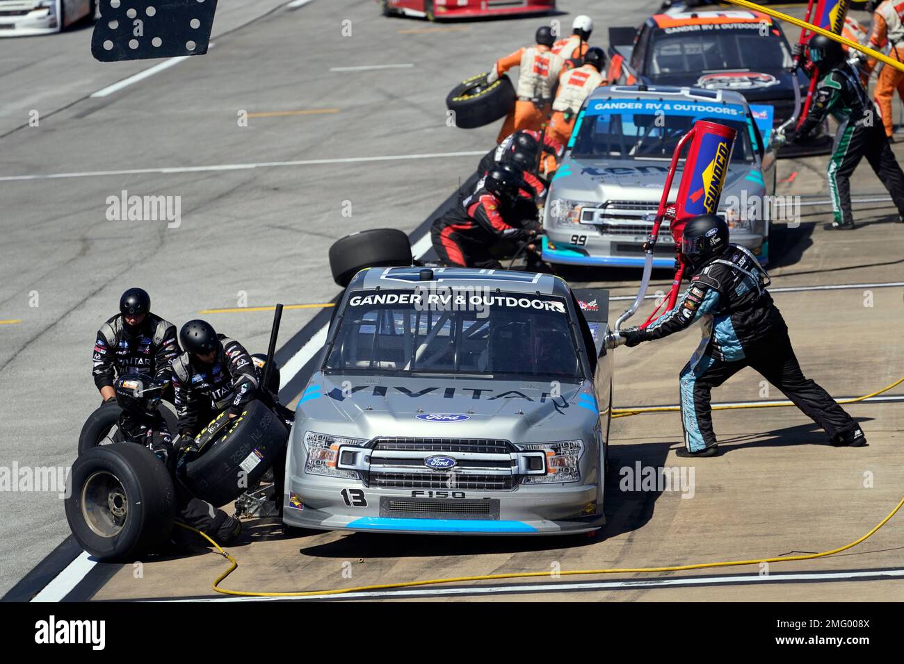 Pit crews work to change tires and refuel Johnny Sauter (13) and Ben ...