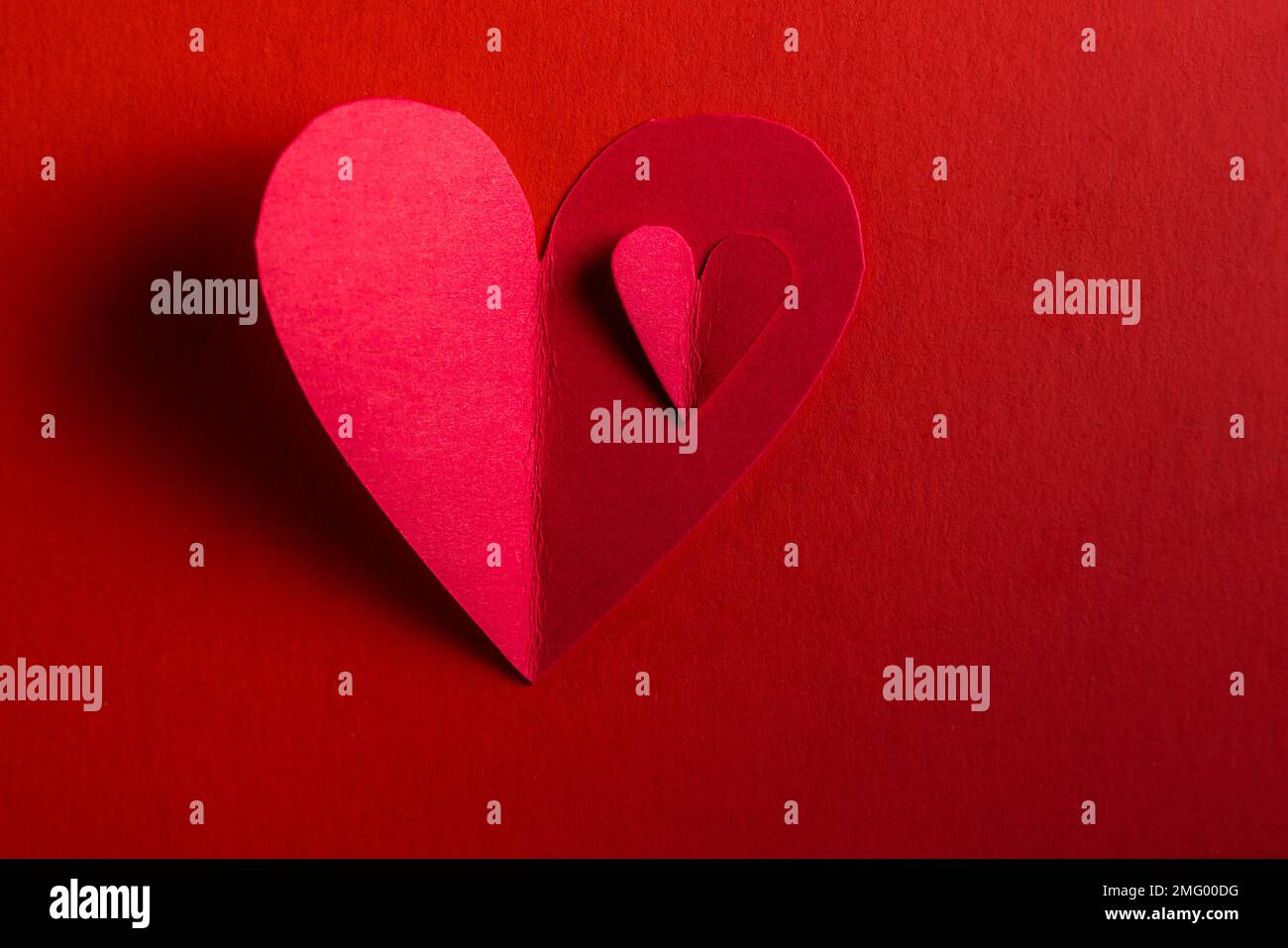 Hand cut hearts out of red paper on a red background Stock Photo - Alamy