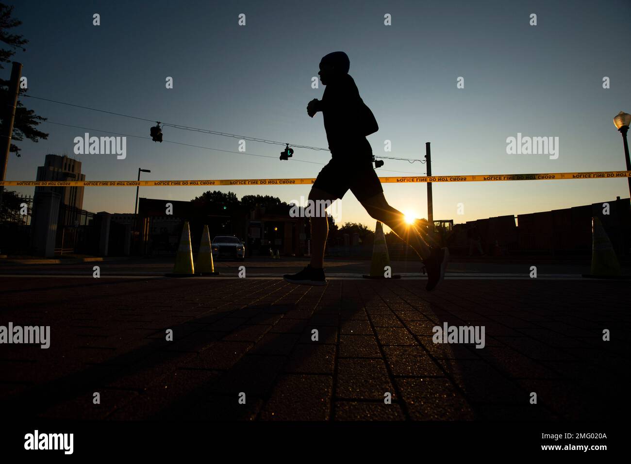 As the sun begins to rise, a runner passes by in front of the main gate ...