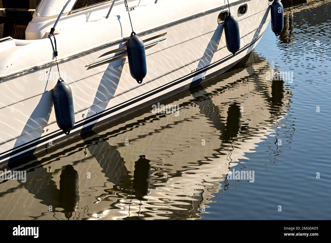 Side view of a speedboat reflected in the srtill water of a harbour. No ...