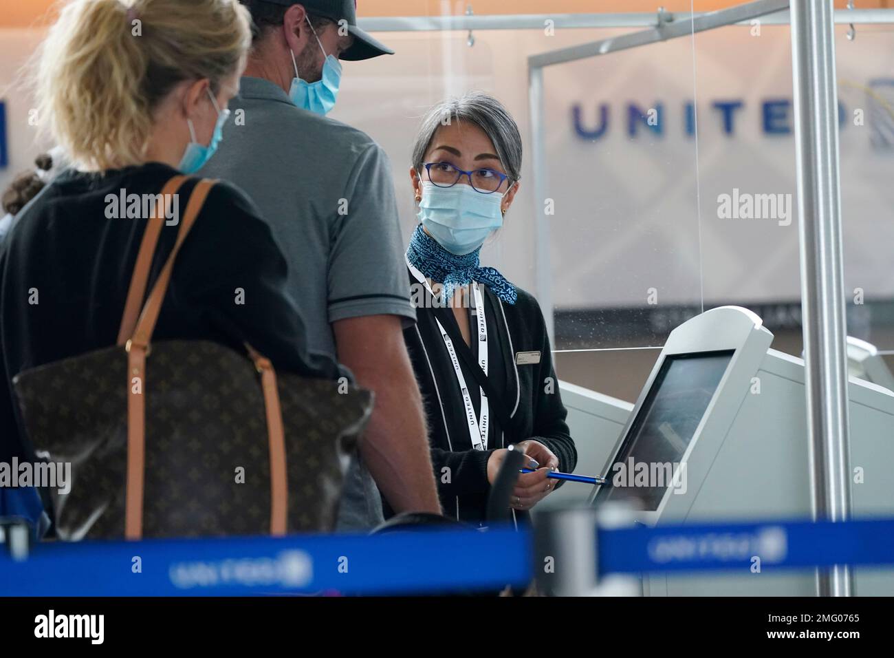 Travellers check in at a United Airlines kiosk with help from a United ...