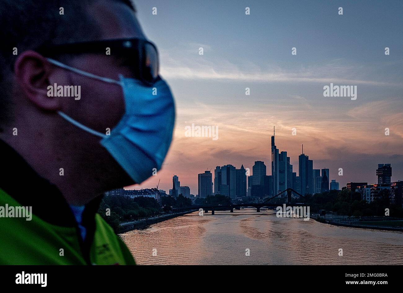 A man wears a face mask as he walks across the bridge over the river ...