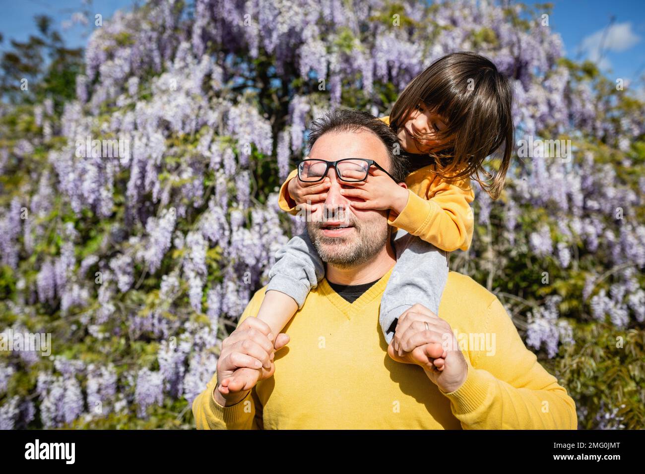 Child sitting on father shoulders closes eyes to a father Stock Photo ...