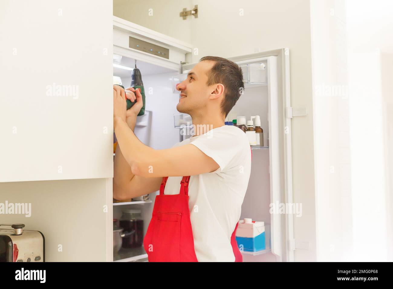 Repairman makes refrigerator appliance troubleshooting and maintenance ...