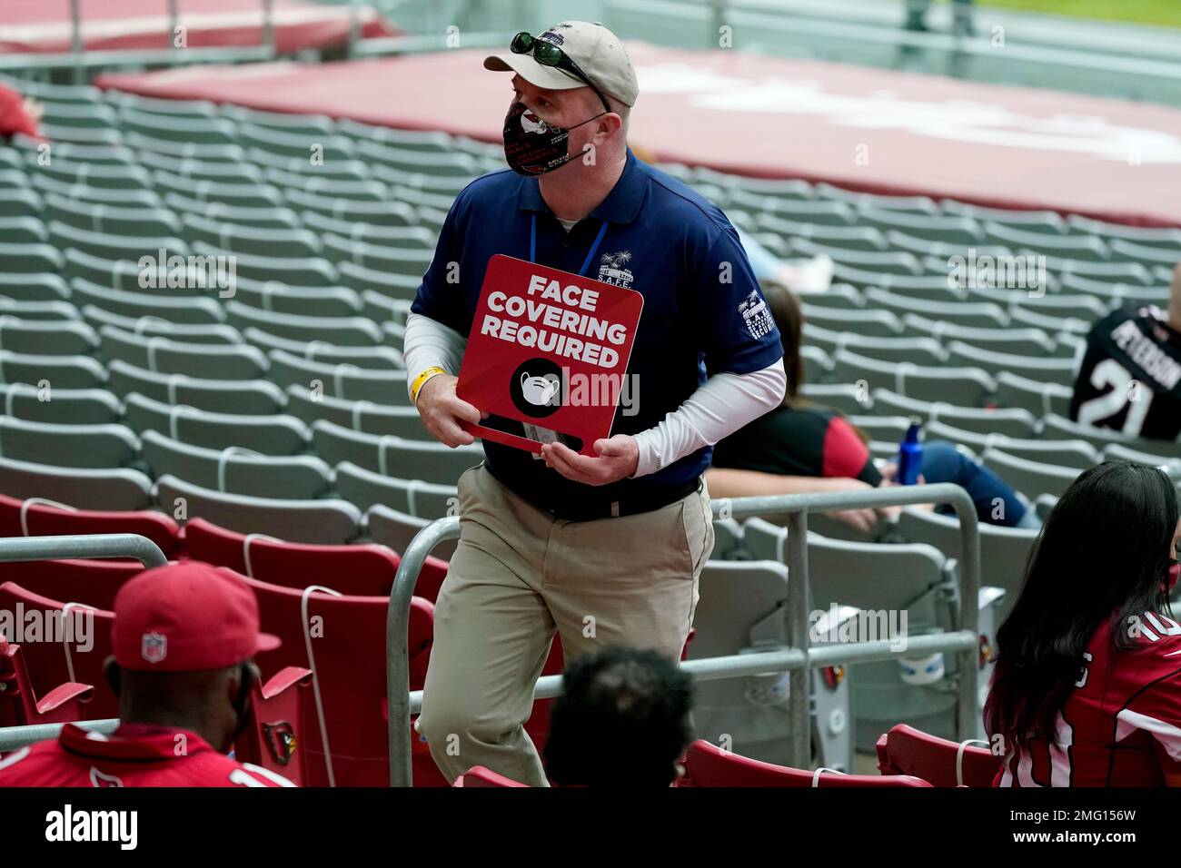 A security official holds a sign reminding fans to wear a face mask ...