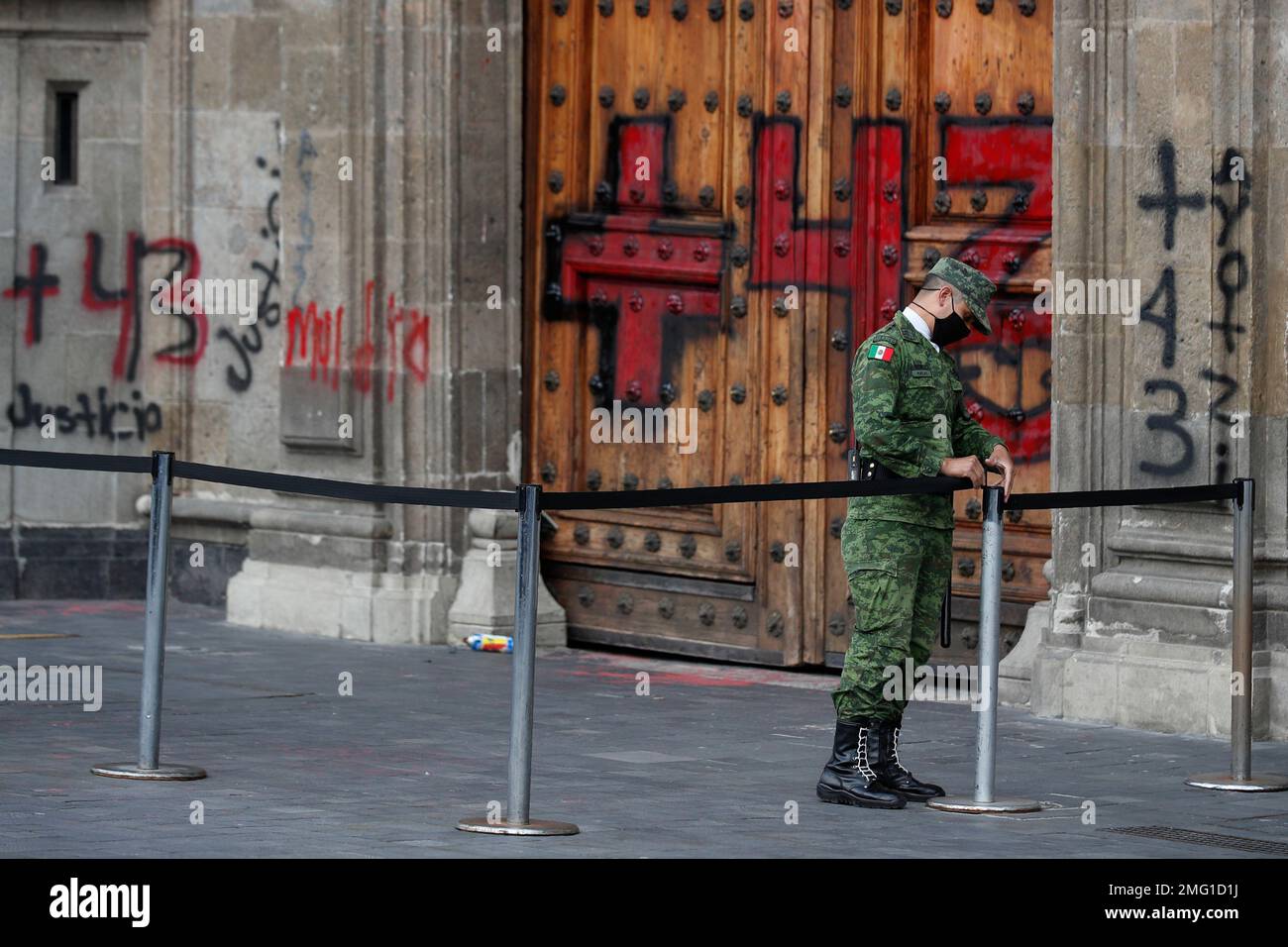 A guard reattaches a security cordon after protesters spray painted the ...