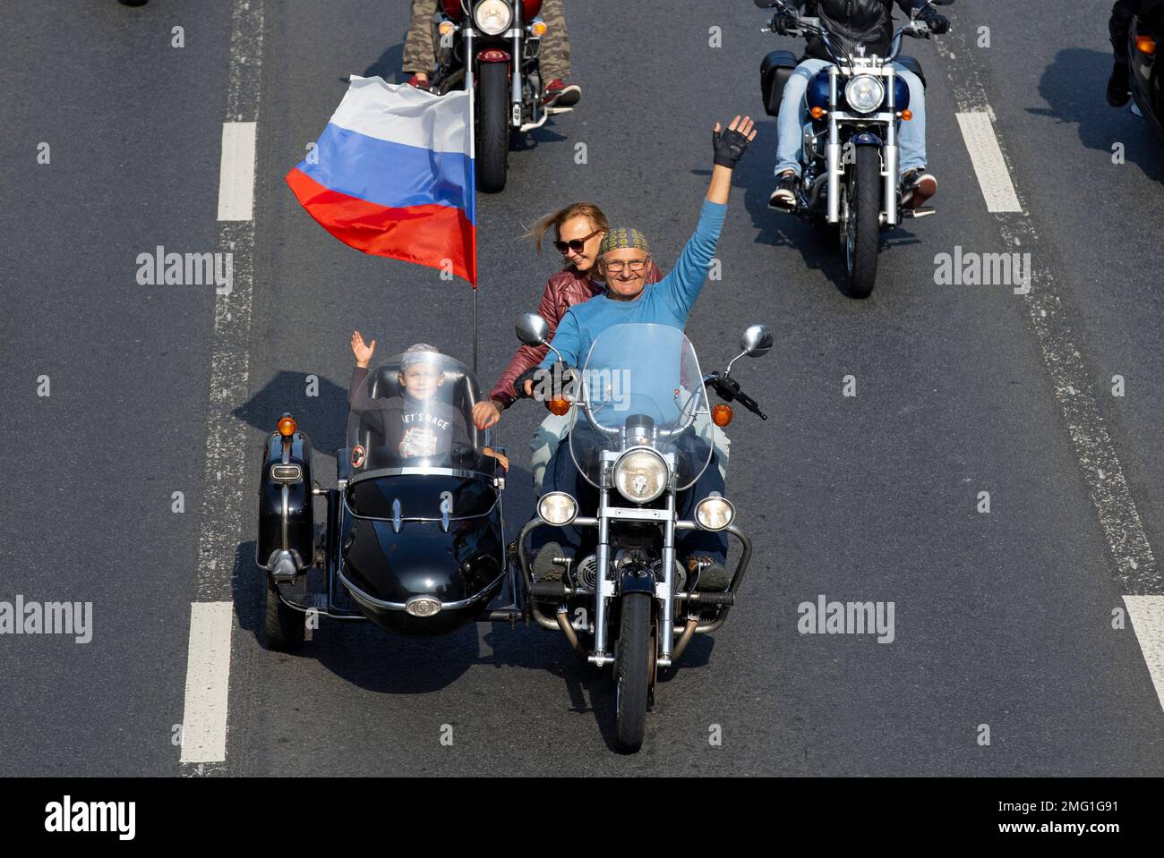 A biker rides with a family member in a 'Ural" Soviet made motorcycle ...