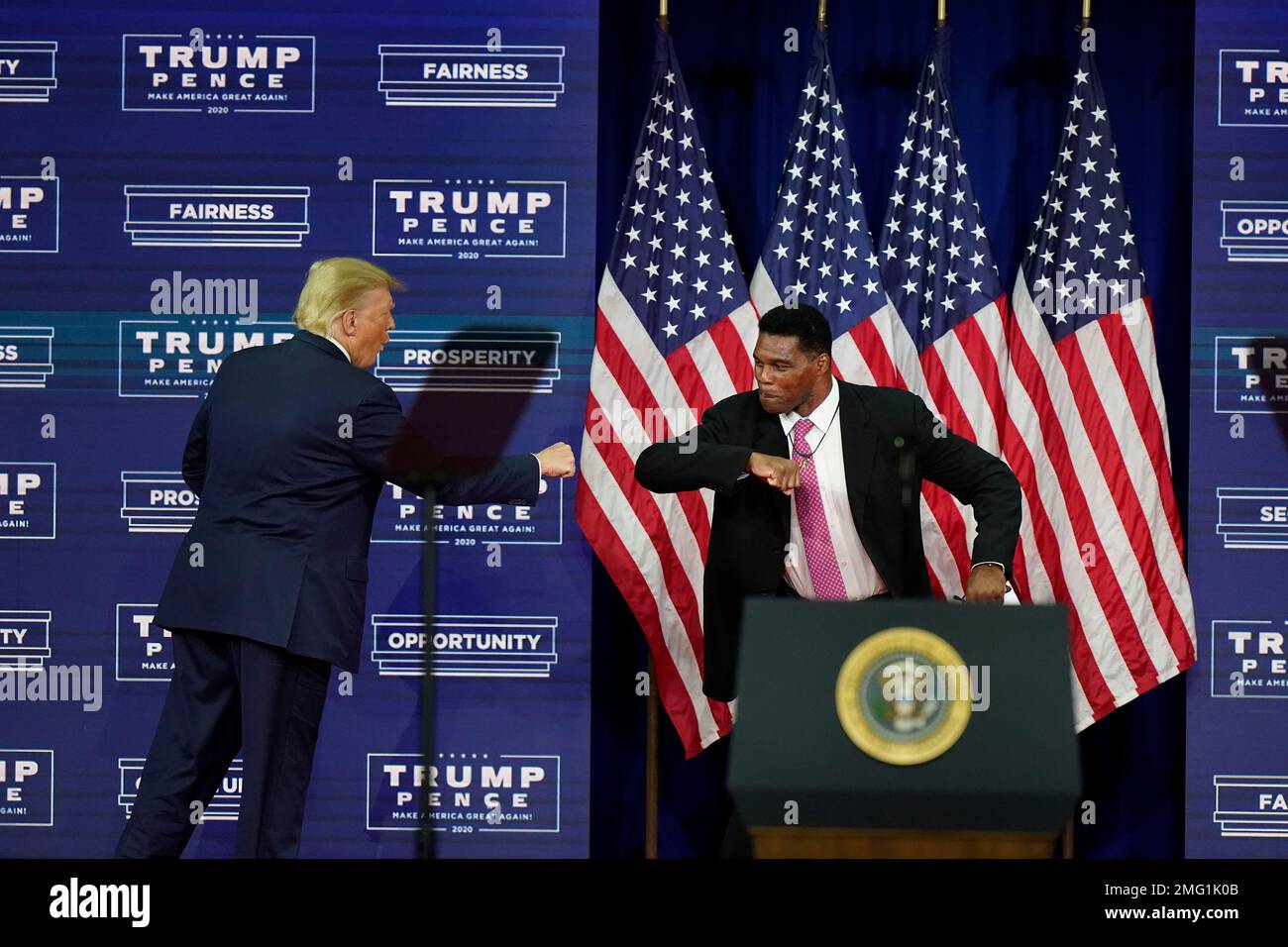President Donald Trump elbow bumbs with Herschel Walker during a ...