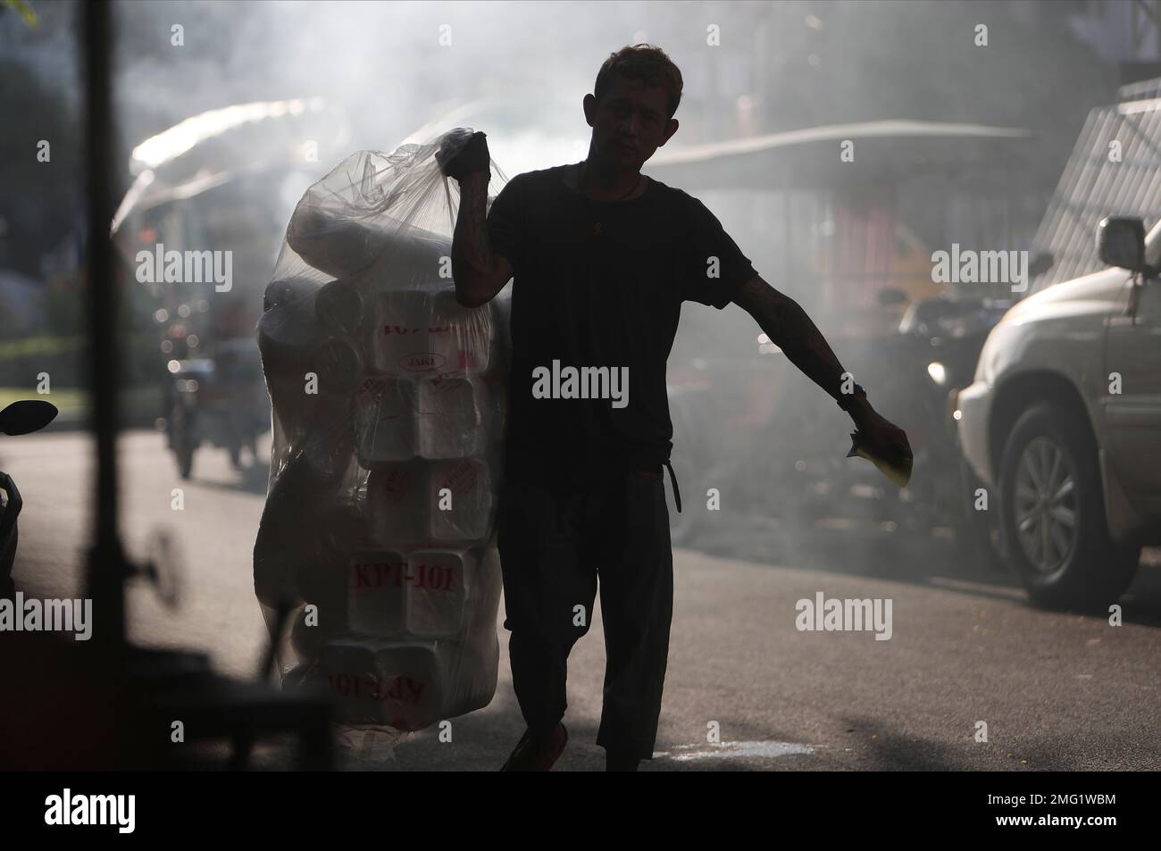 A man carries styrofoam boxes for packing cooked rice at a sidewalk ...