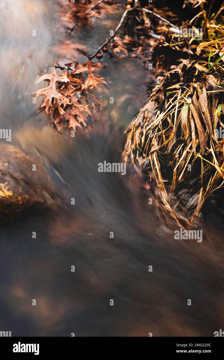 A small rivulet of water passes through a tiny chute in a stream on an ...