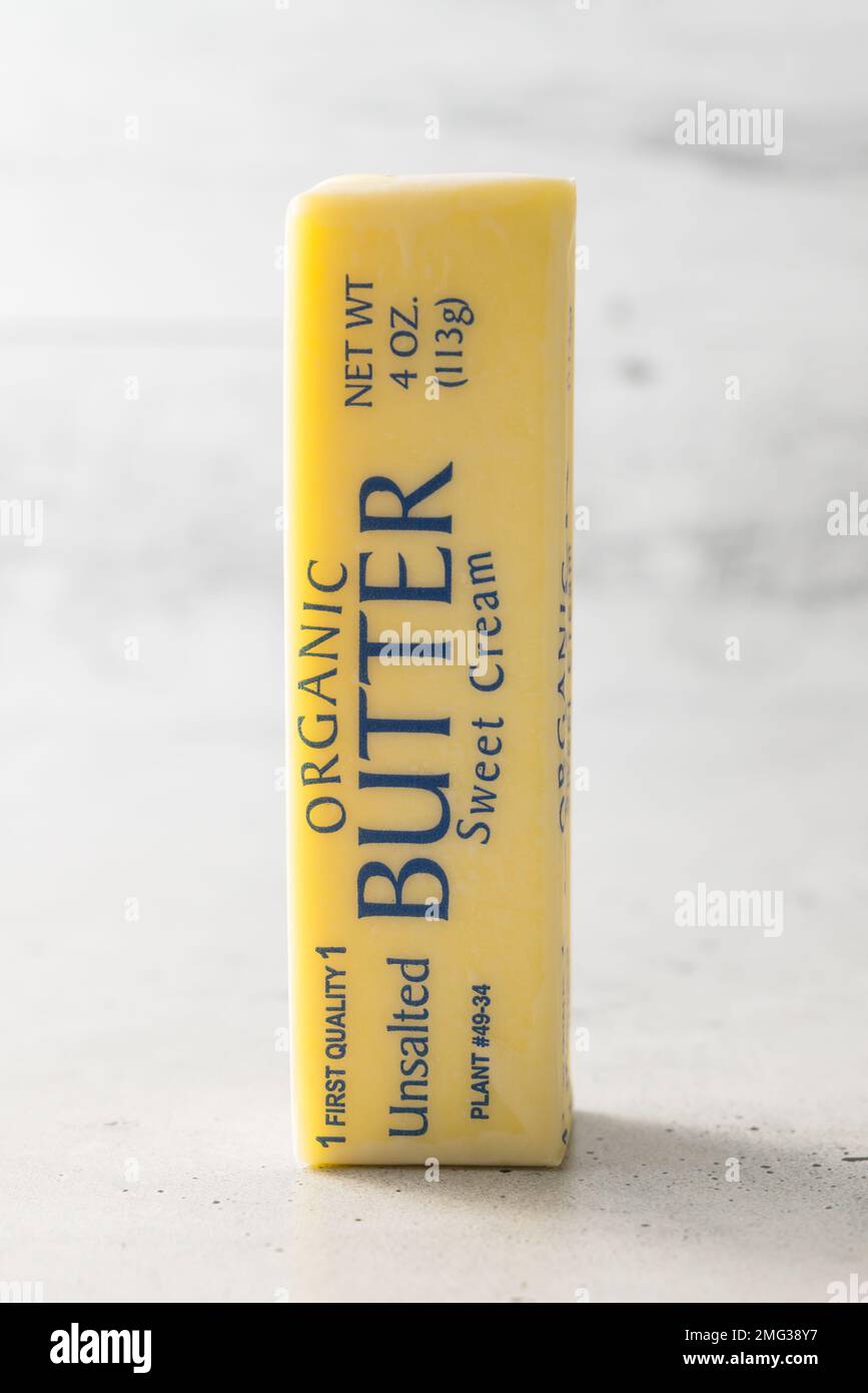 One stick of organic unsalted butter close-up on a light grey ...