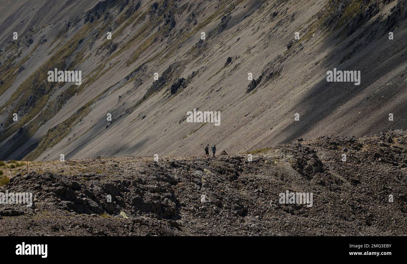Two active hikers walking on exposed mountain ridge path trail in ...