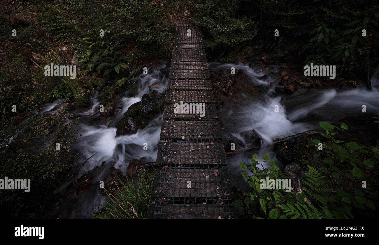 Long exposure of simple wooden footbridge path walkway over white water ...