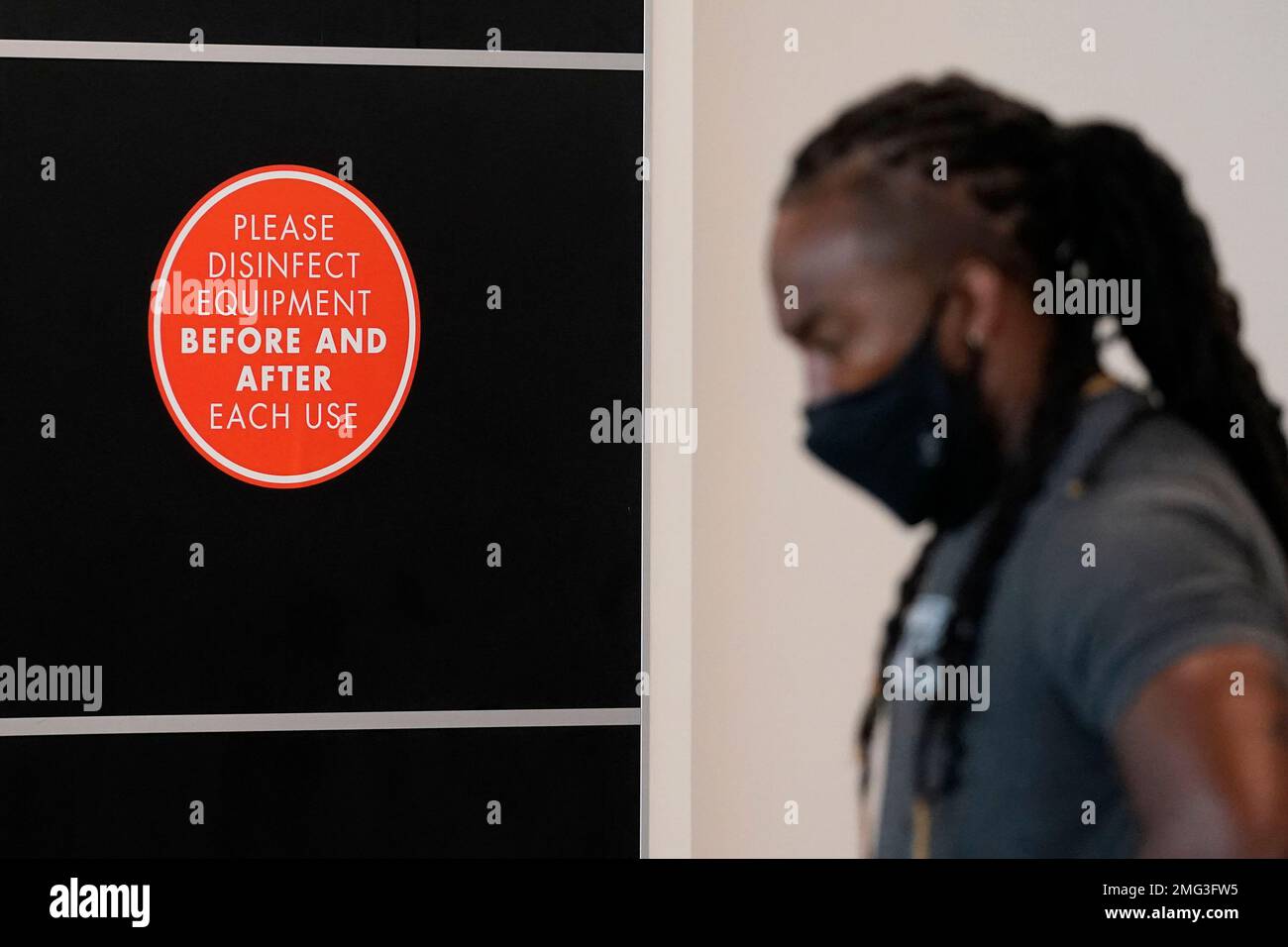 A sign advising people to disinfect workout equipment is displayed ...