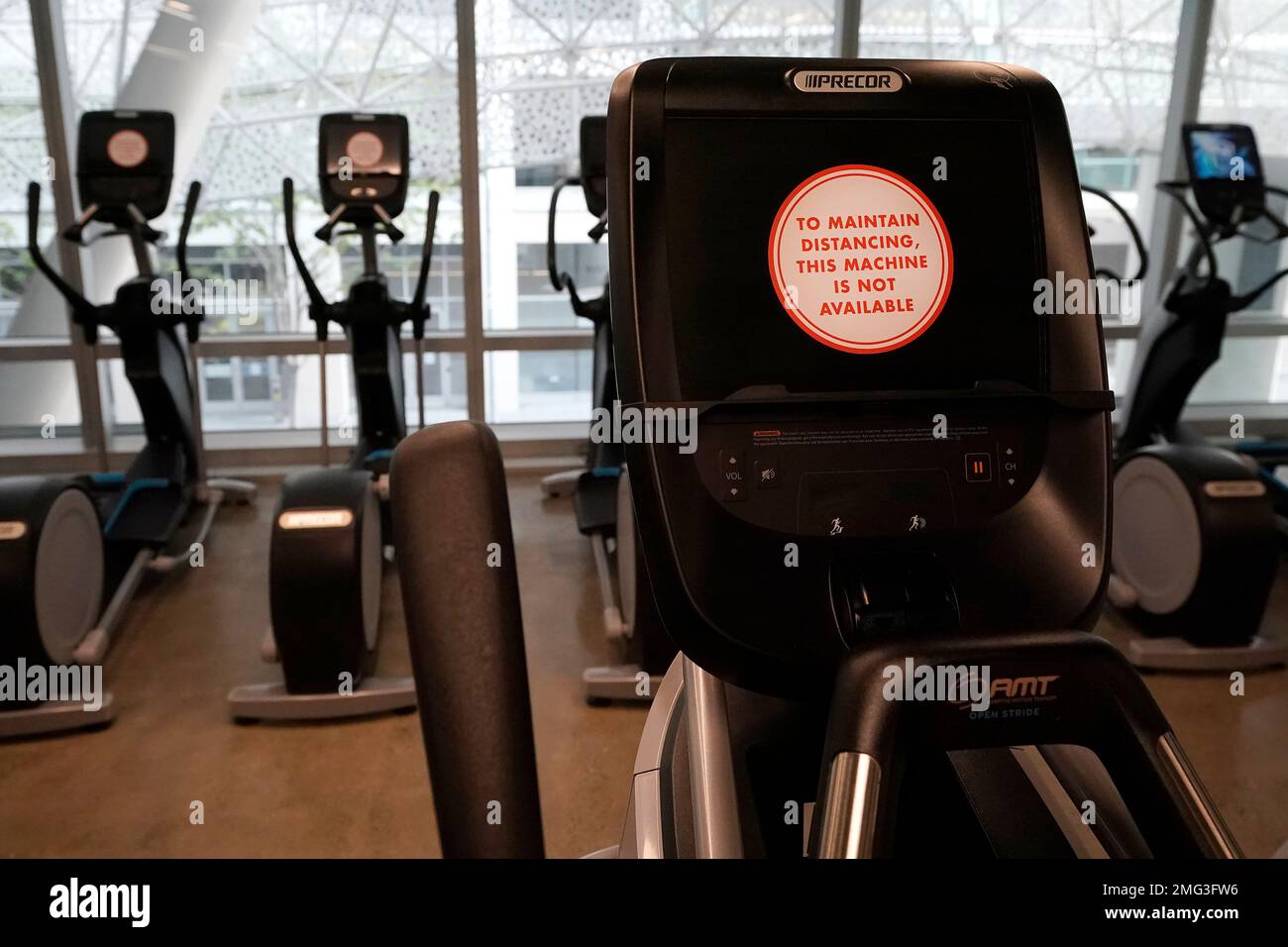 A sign advising gym members to maintain distance is posted on an ...