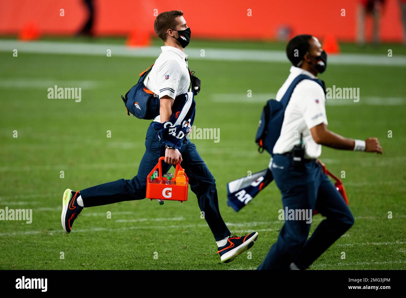Staff from the Denver Broncos jog on the field with Gatorade products ...