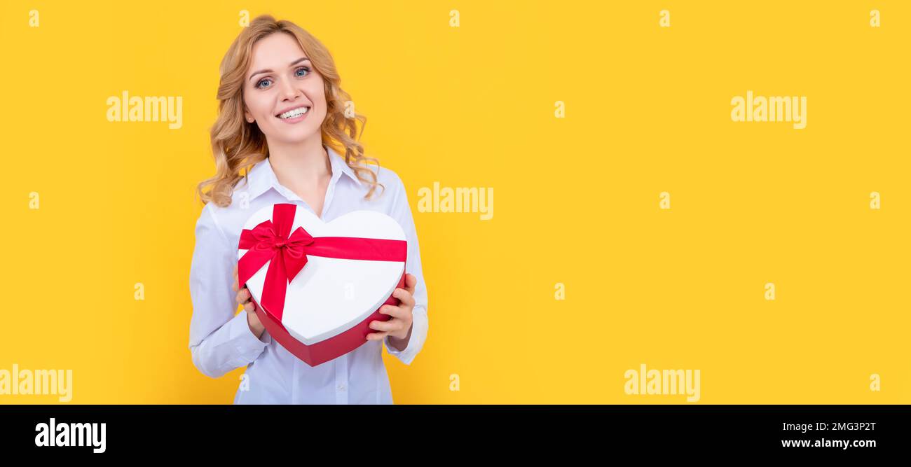 glad woman hold present heart box on yellow background. Woman isolated ...