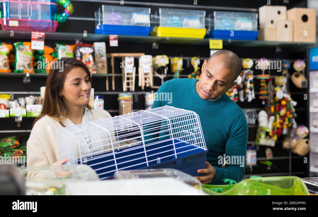 Man helping woman to choose hamster cage at store Stock Photo - Alamy