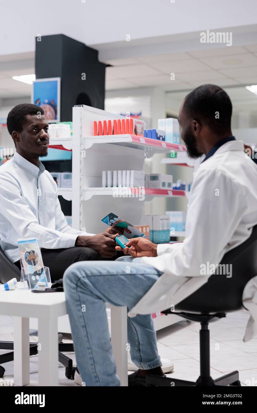 African american pharmacist measuring patient blood sugar with ...