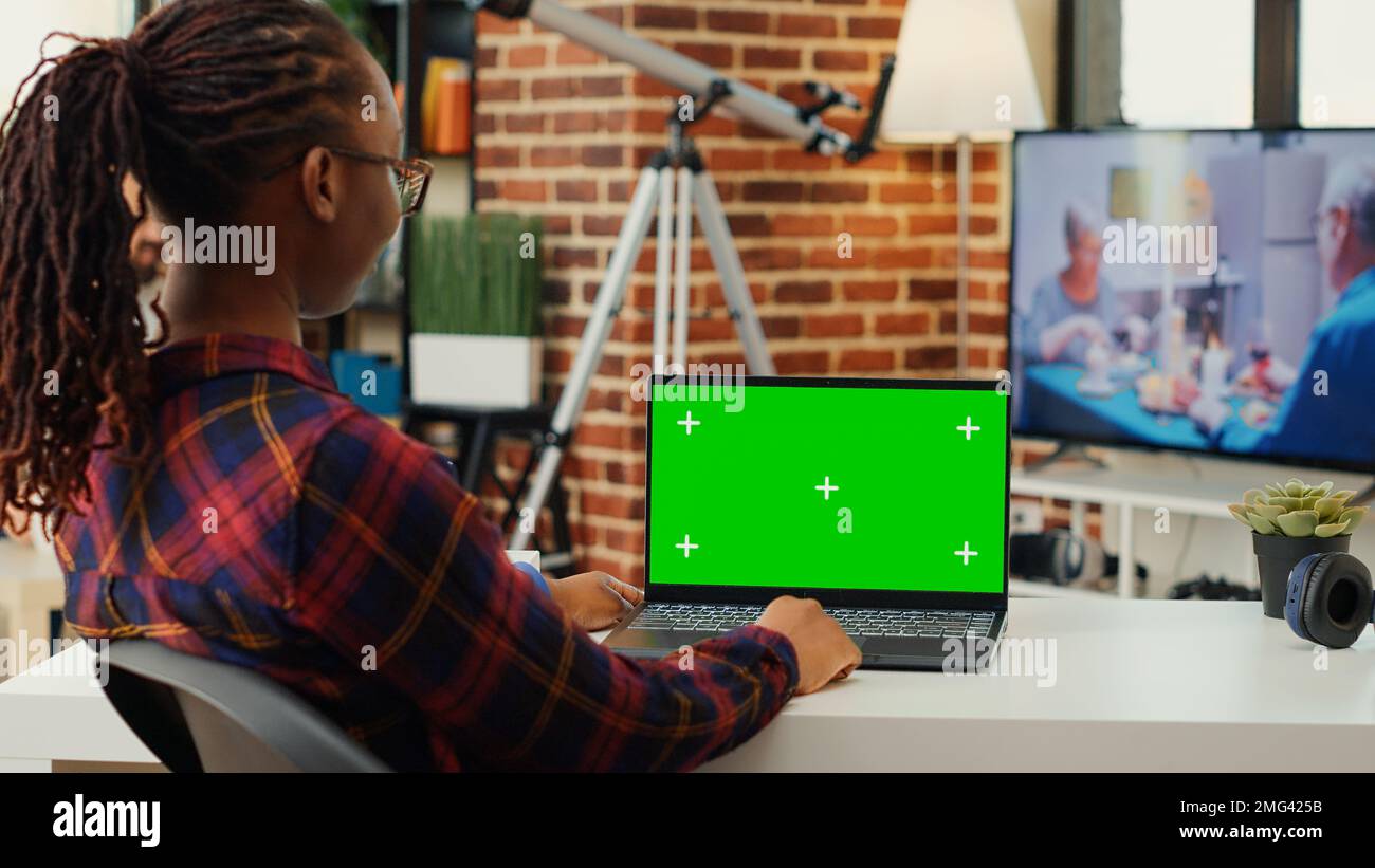 Female employee looking at greenscreen display on laptop, using ...
