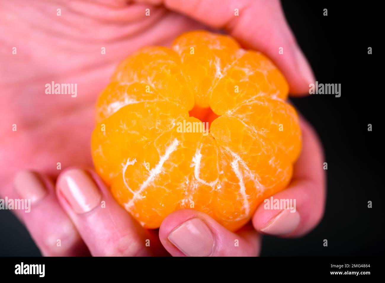Fresh fruit. One peeled mandarin in woman hand Stock Photo - Alamy