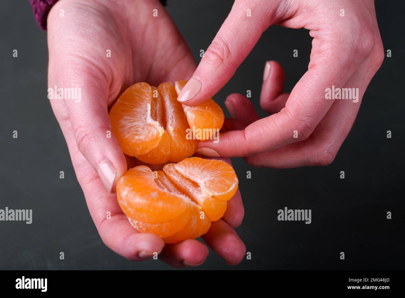 Fresh fruit. One peeled mandarin in woman hand Stock Photo - Alamy