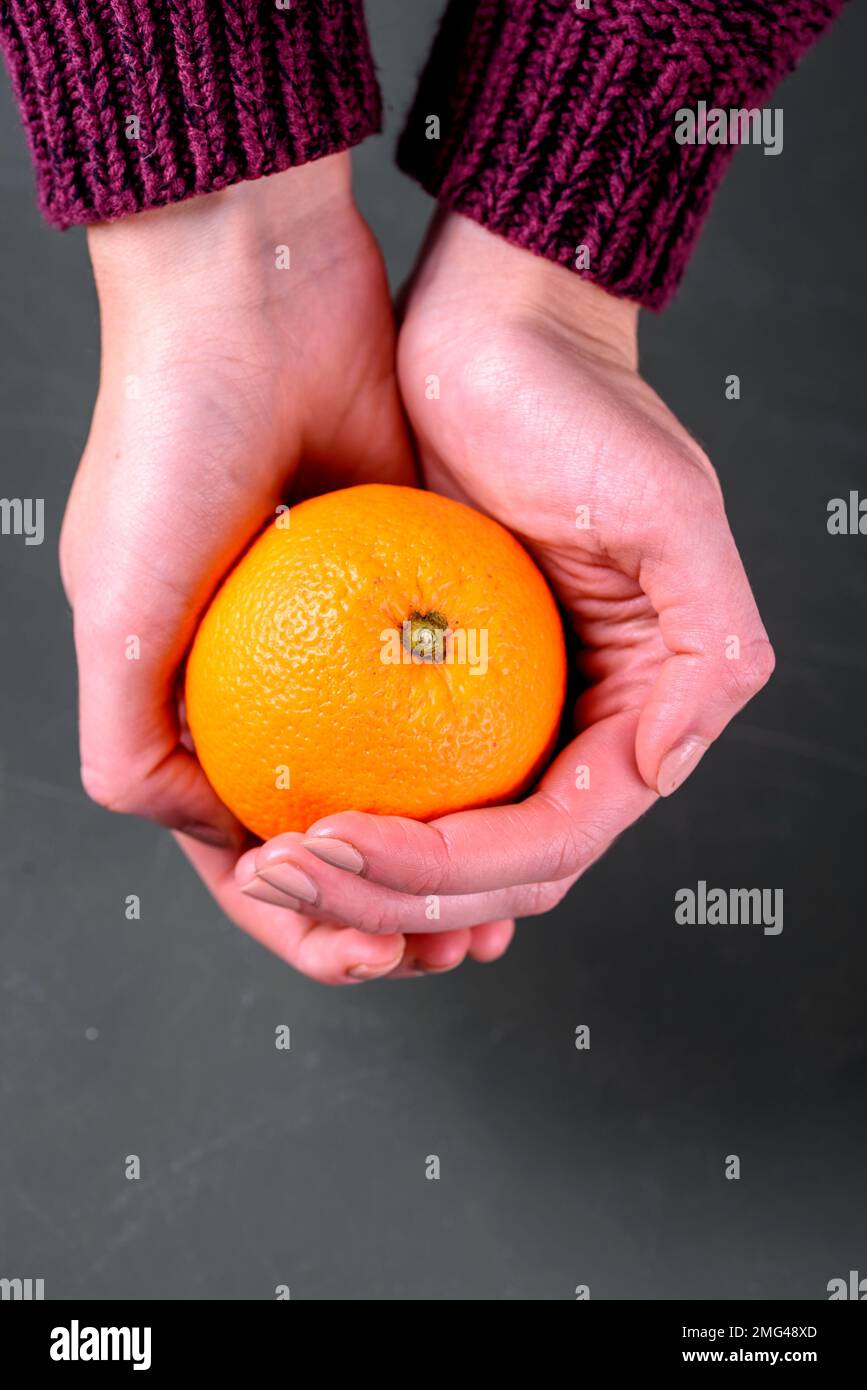 Fresh fruit. One fresh orange in woman hands Stock Photo - Alamy