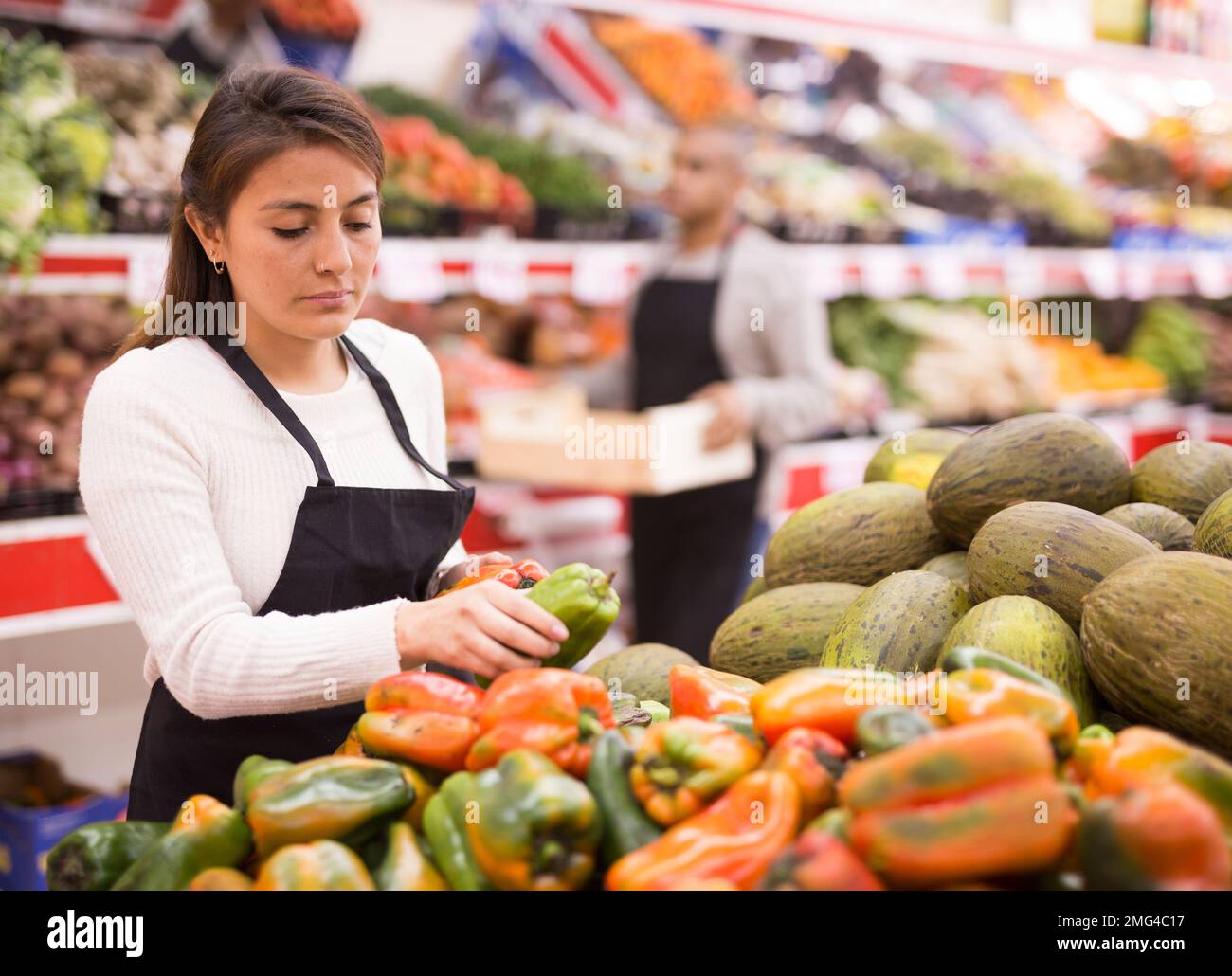 Supermarket woman worker in black apron putting vegetables in her ...