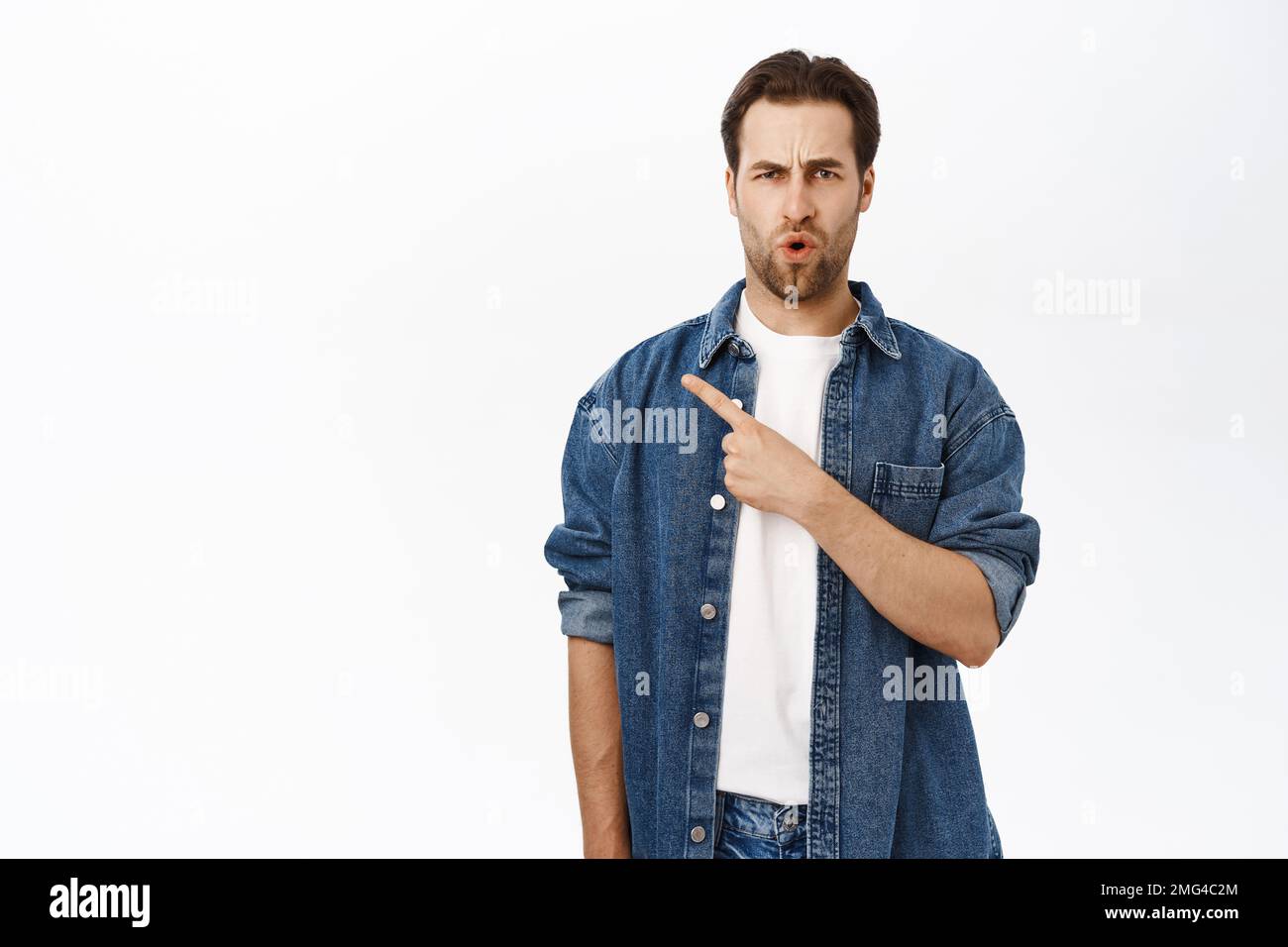 Portrait of impressed guy pointing finger left, showing smth shocking ...