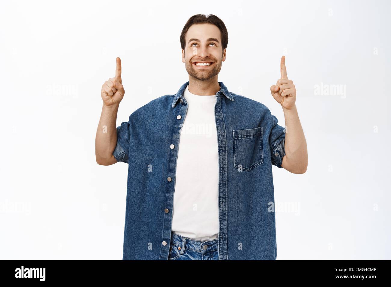Handsome smiling man pointing fingers up, shows banner or advertisement ...