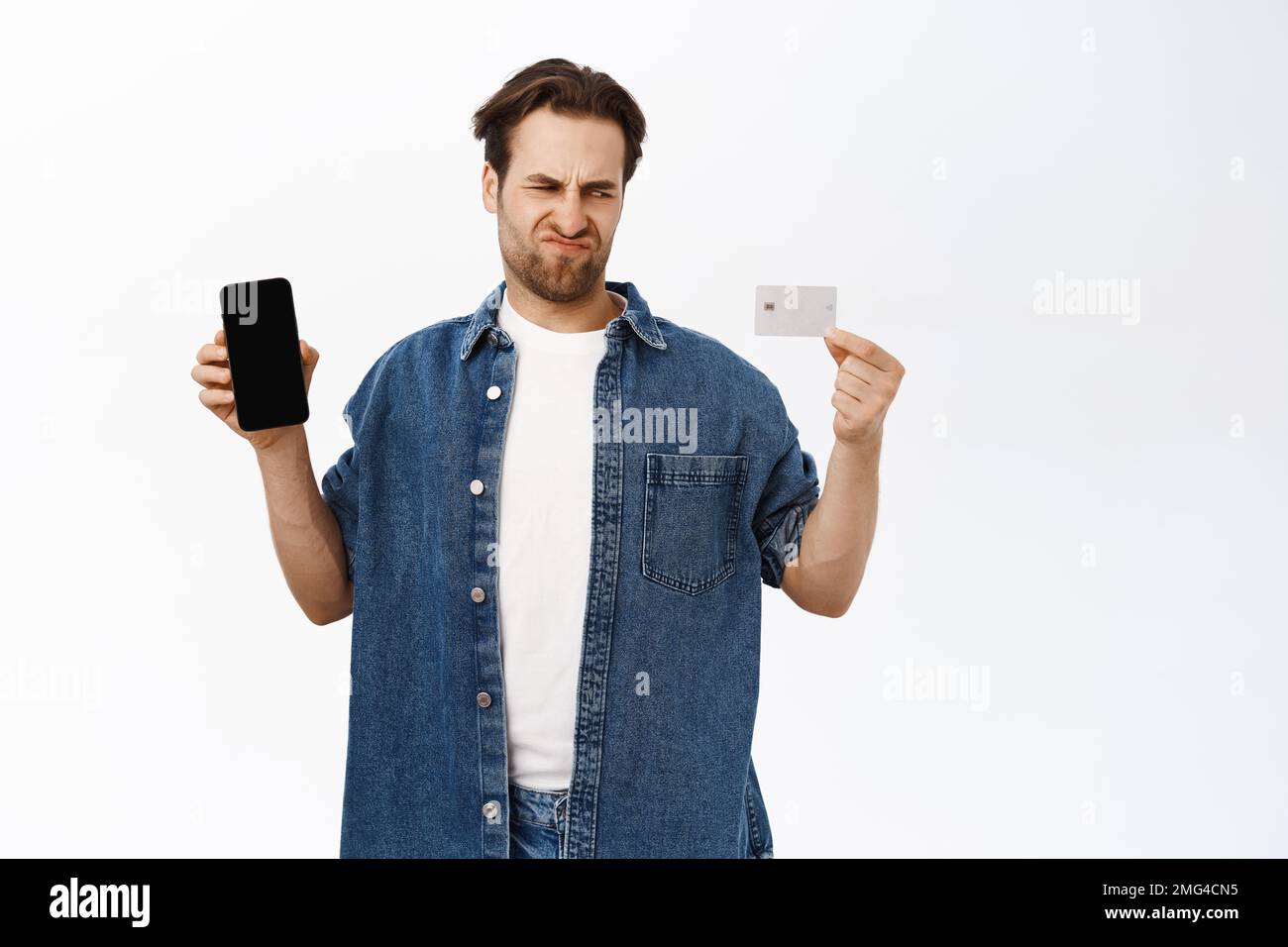 Disappointed young man shows mobile phone screen, looks disappointed at ...