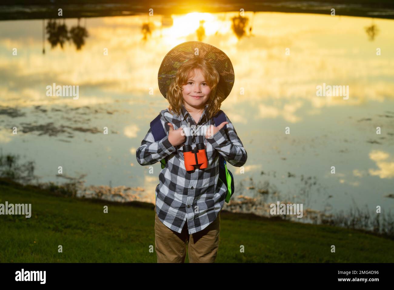 Cute blond kid with binoculars wearing explorer hat and backpack on ...
