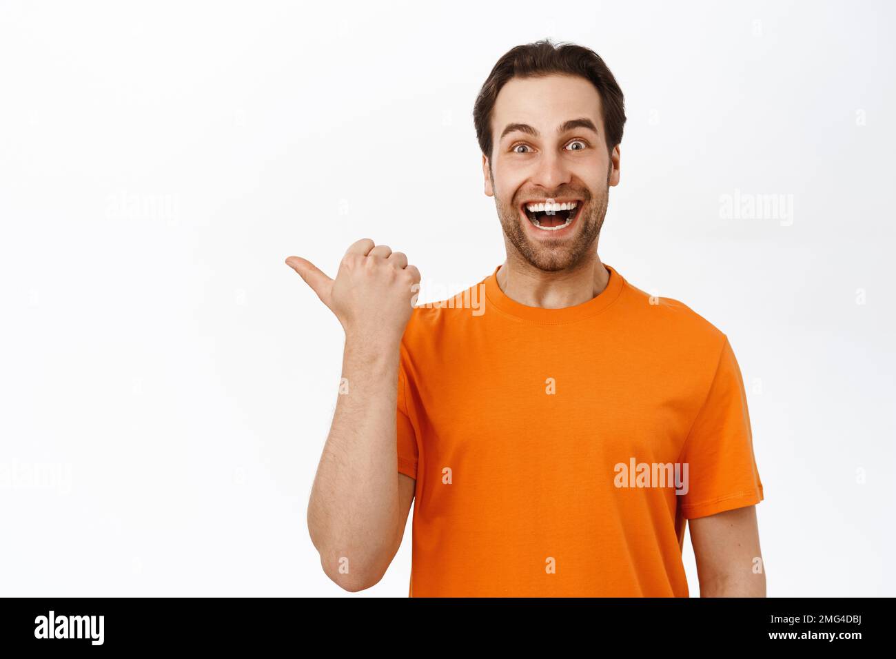 Close up of enthusiastic adult man pointing left, smiling amazed ...