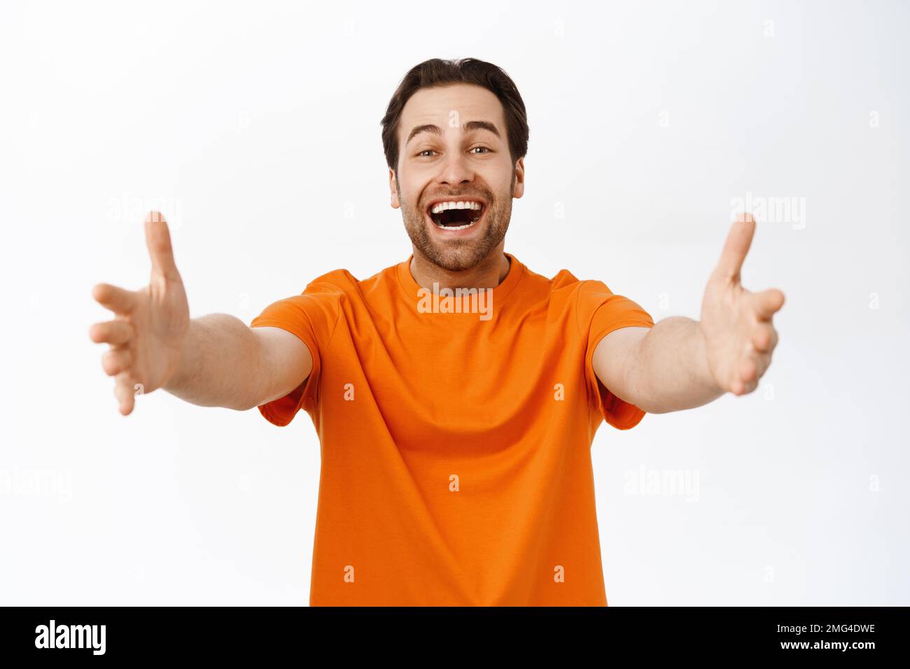 Enthusiastic young man inviting you to hug, extending hands, reaching ...