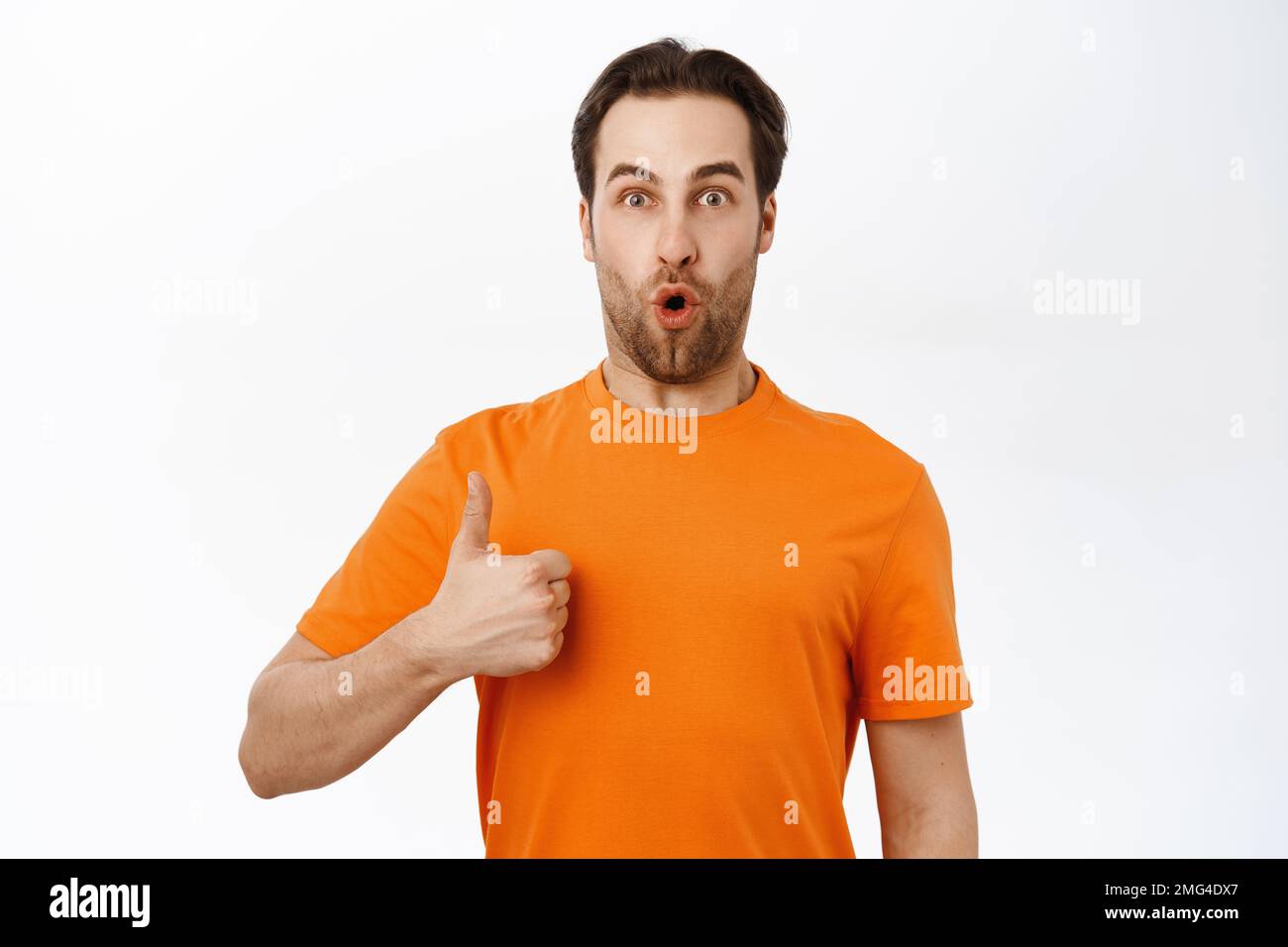 Man with impressed face shows thumbs up, recommends smth awesome ...