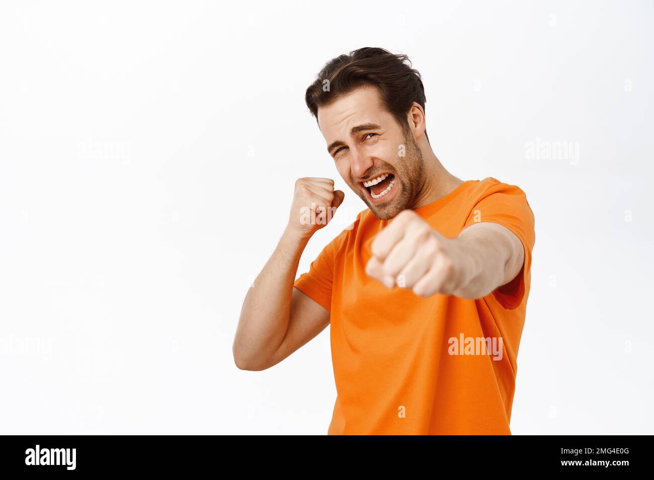 Screaming guy punching, extends his fist, fights, stands in orange ...