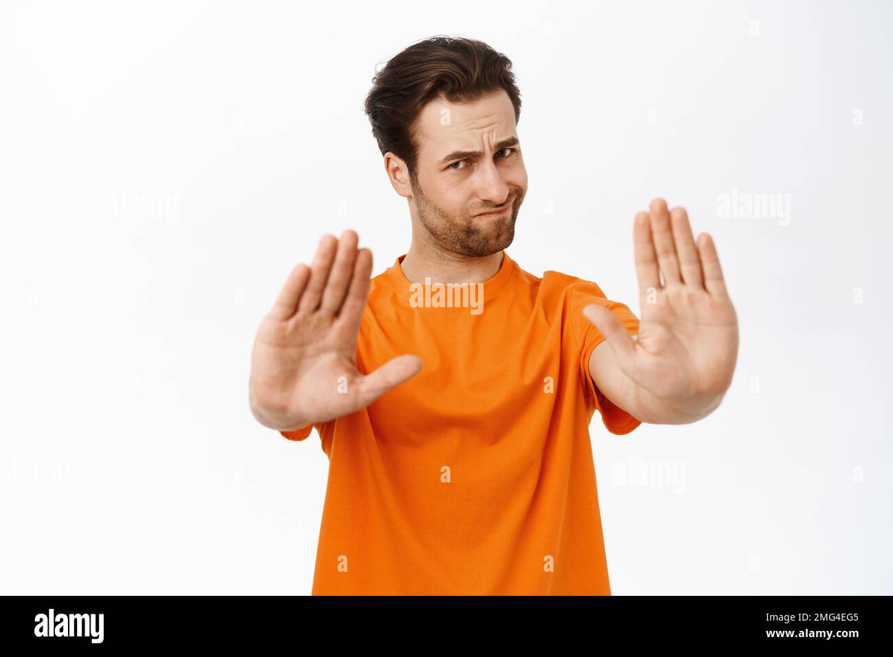 Portrait of brunette man say stop, prohibit smth, stretching out hand ...