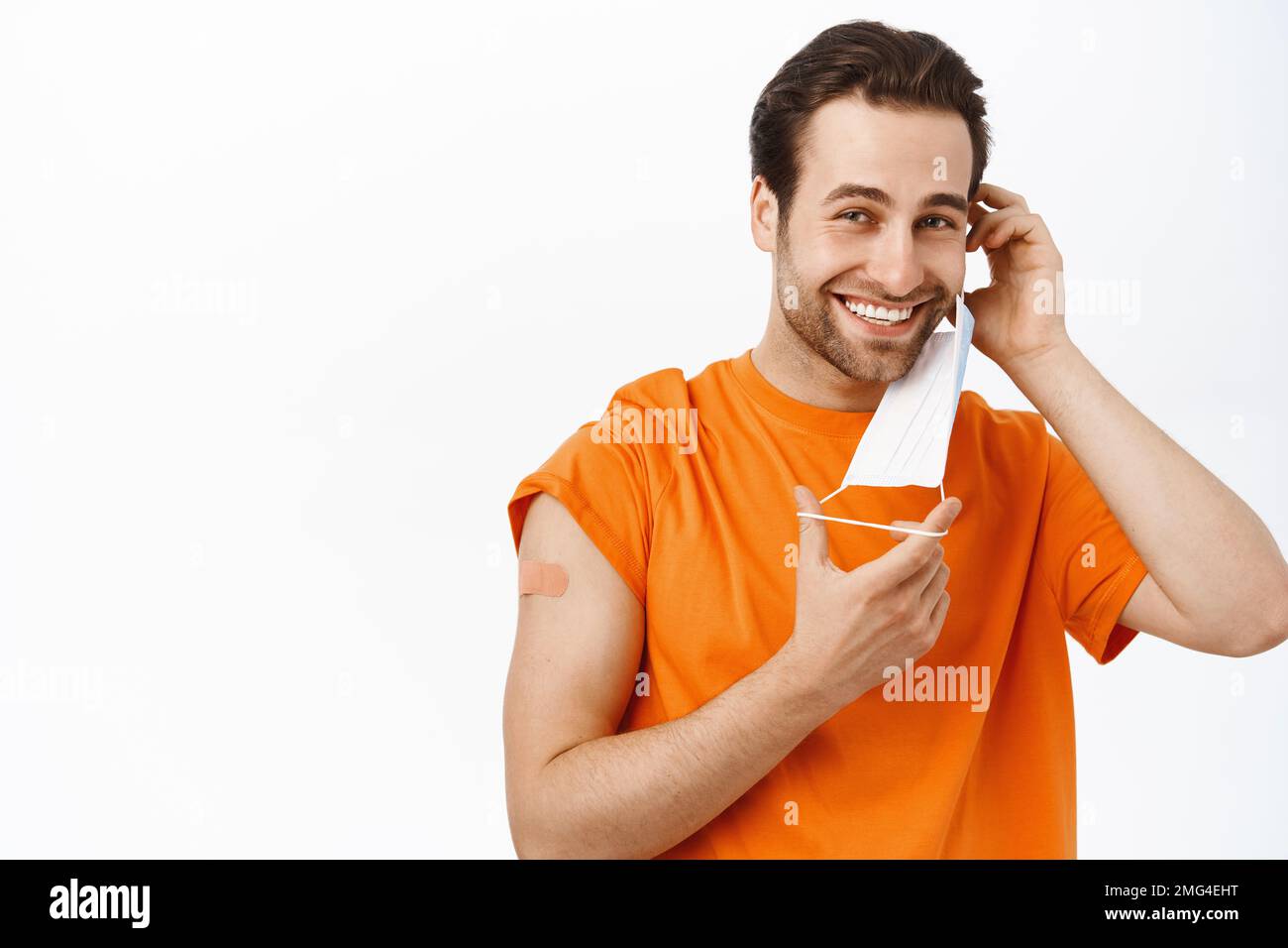 Smiling healthy man puts on medical face mask to prevent catching covid ...