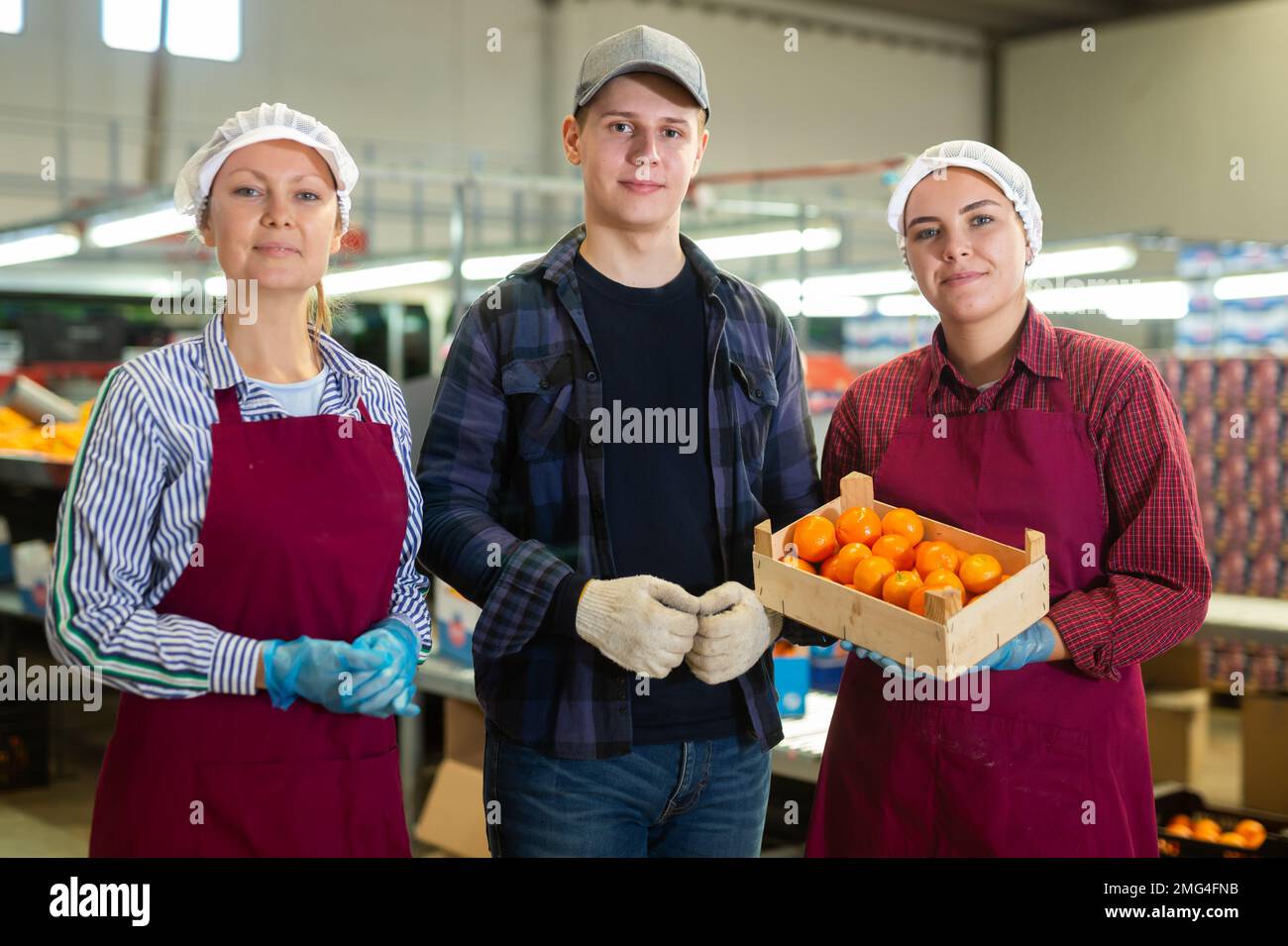 Positive fruit sorting factory workers standing with selected ...