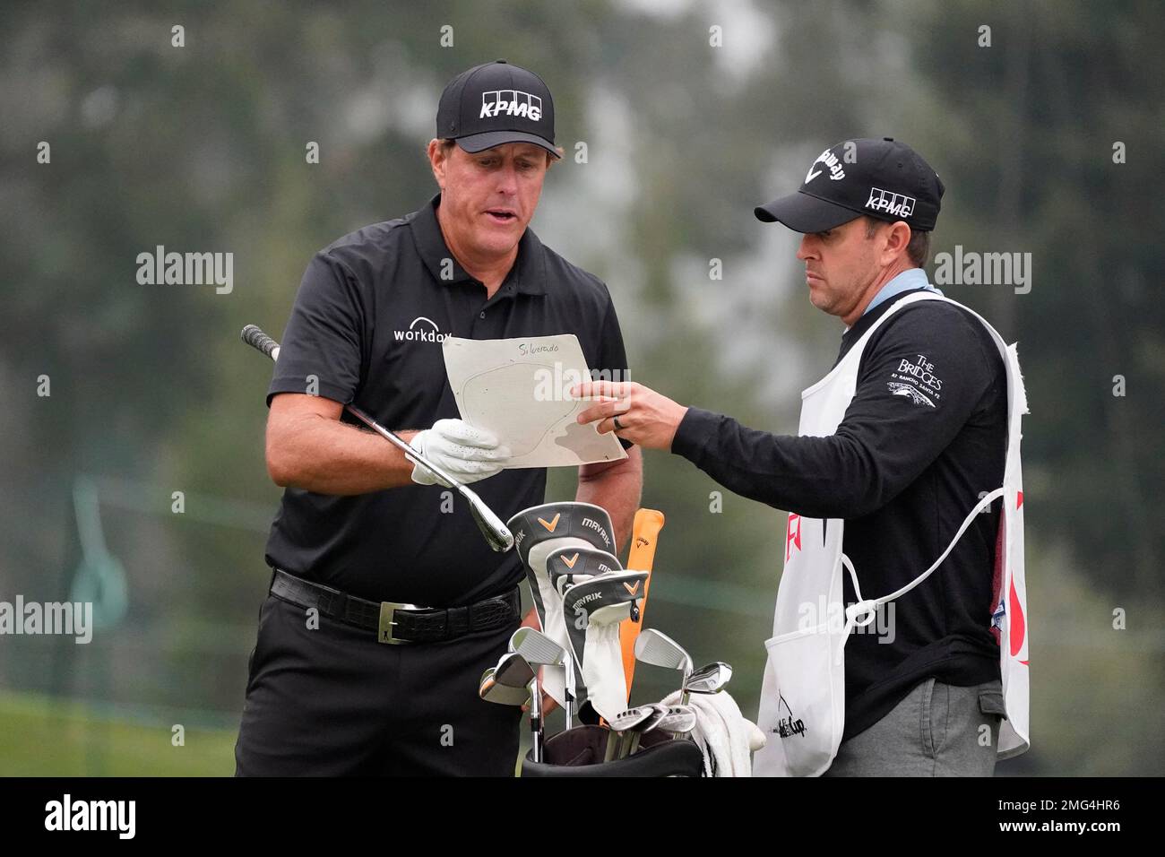 Phil Mickelson, left, looks over a green map with his caddie and ...