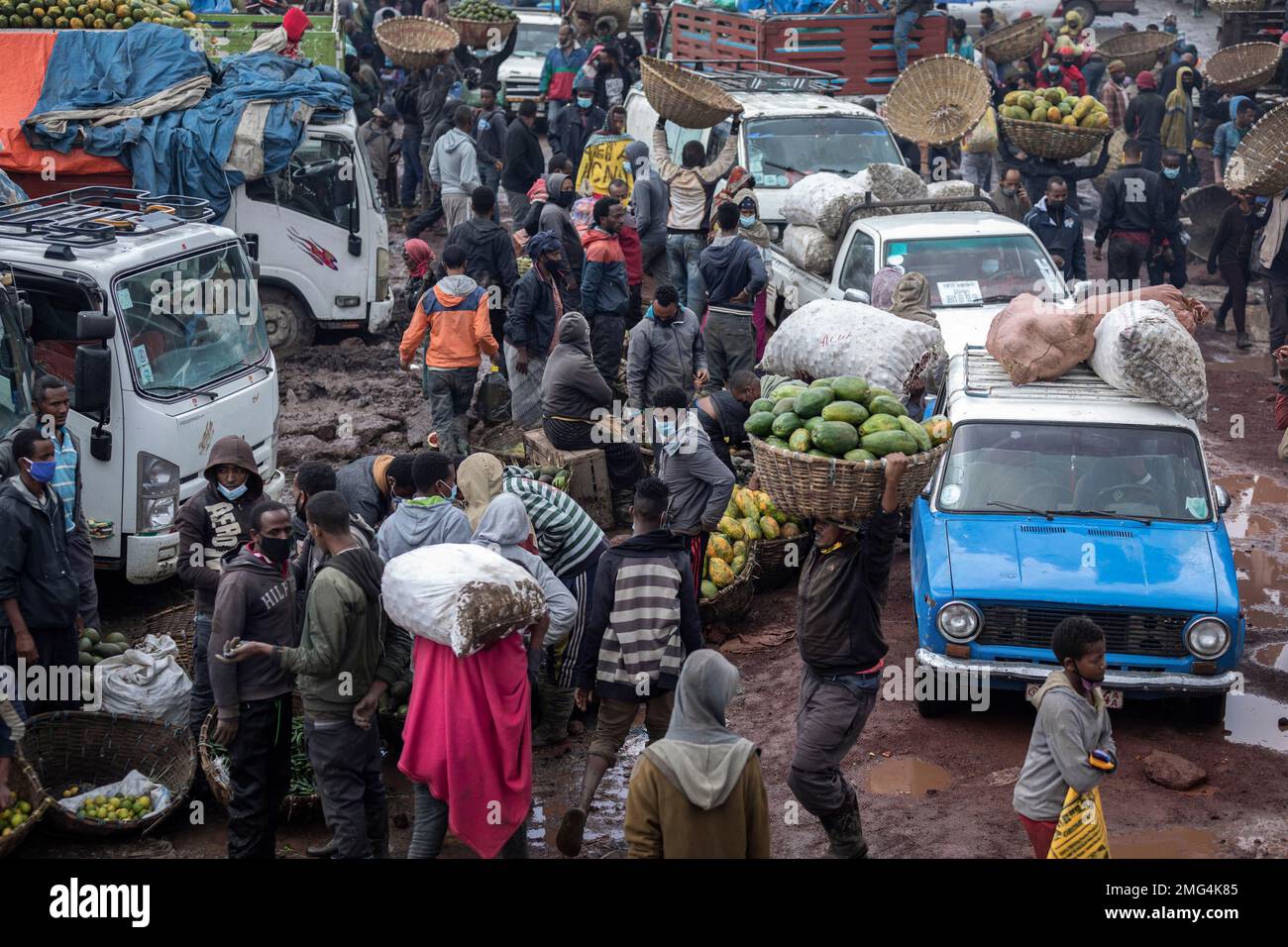 Traders carry baskets of vegetables through muddy pathways in Atkilt ...