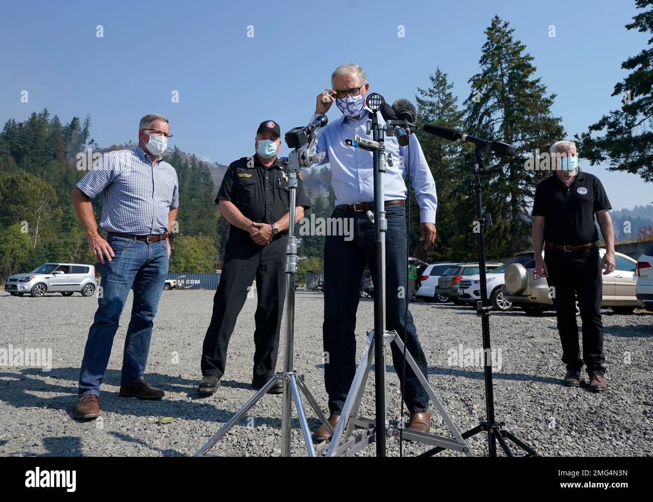Washington Gov. Jay Inslee, center, adjusts his face mask as he arrives ...